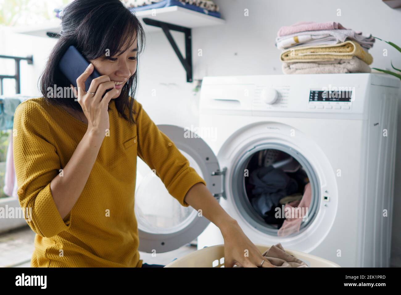 woman in front of the washing machine doing some laundry loading ...