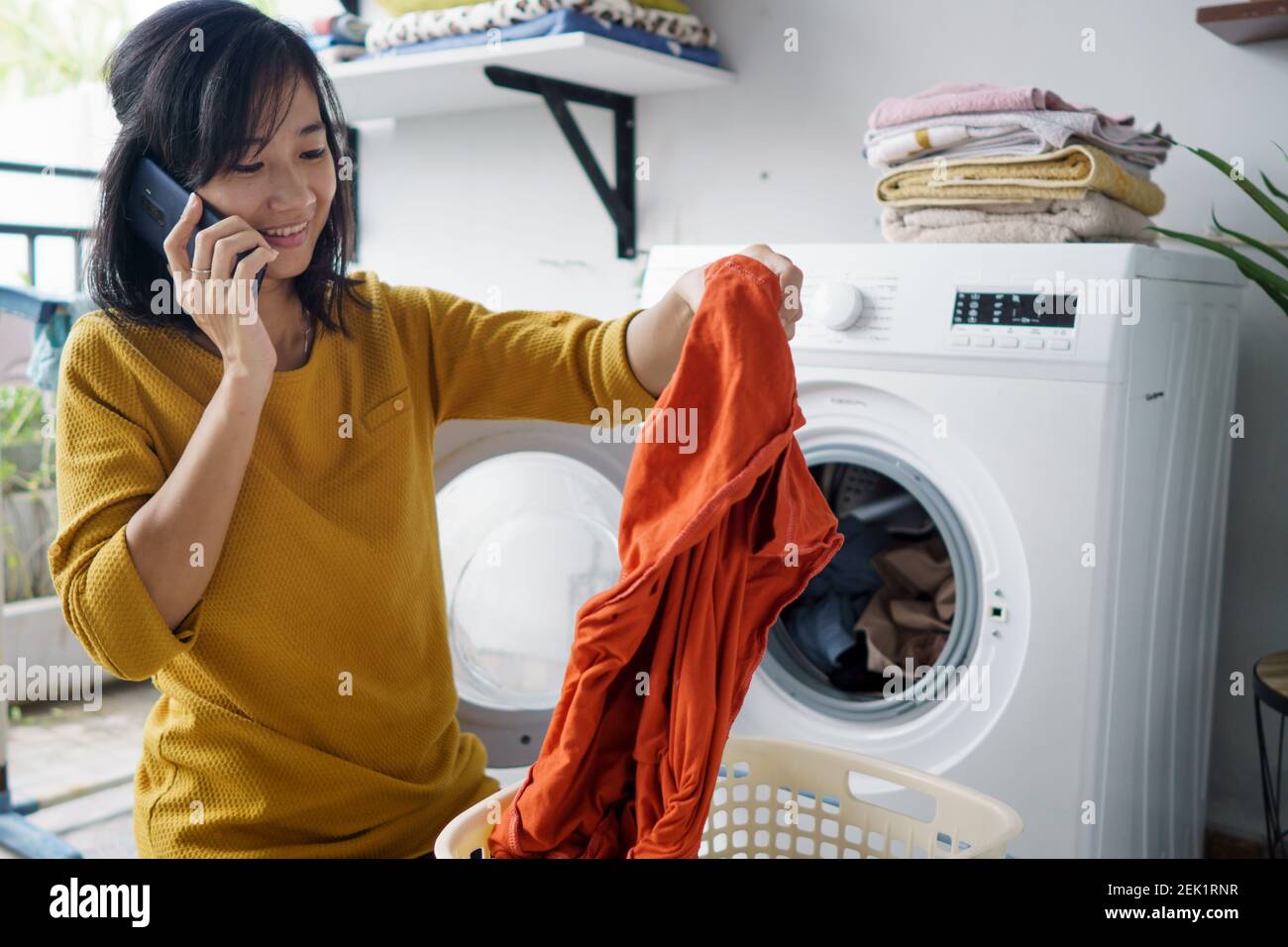 woman in front of the washing machine doing some laundry loading ...
