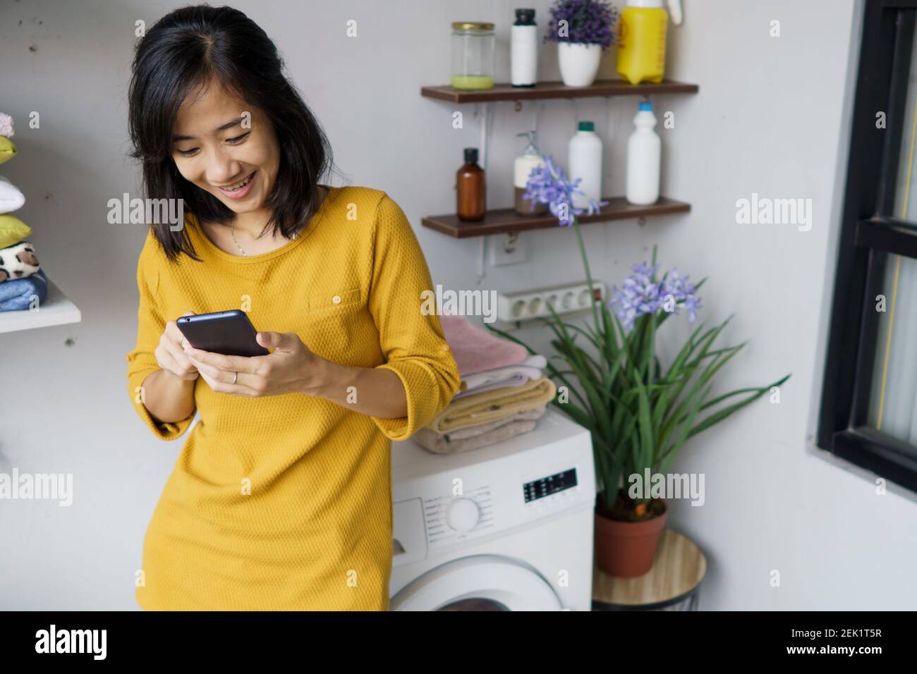 woman in front of the washing machine doing some laundry loading ...
