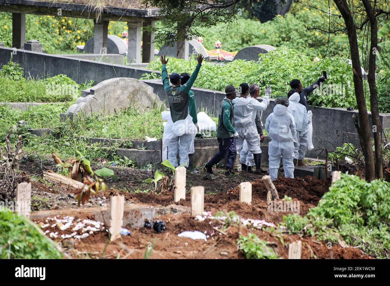 Cemetery employees wearing protective gear take a photo group with a ...