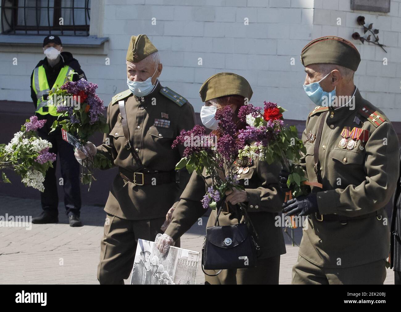 Veterans carry flowers while wearing face masks as a precaution during ...