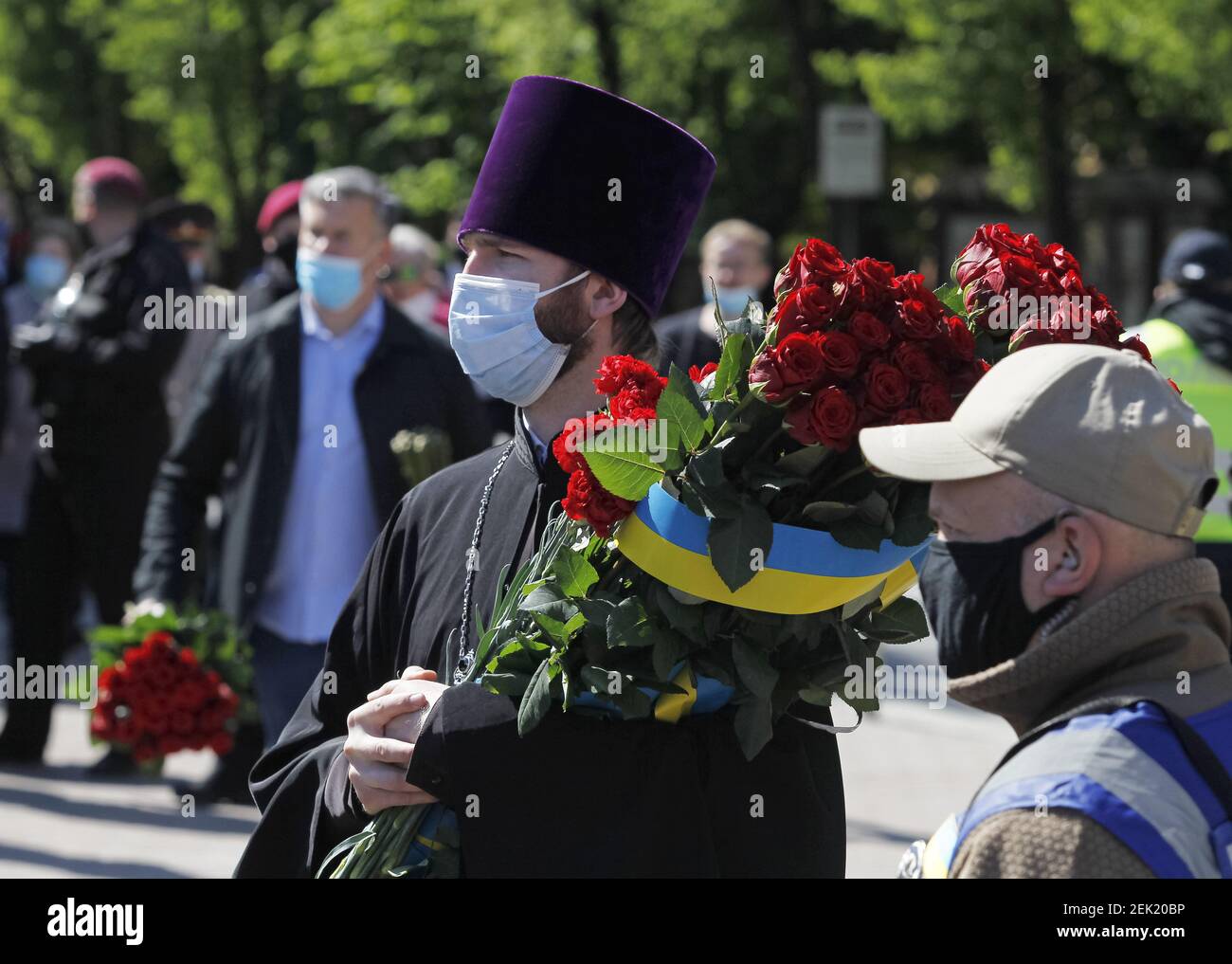 Orthodox priest carries flowers while wearing a face mask as a ...