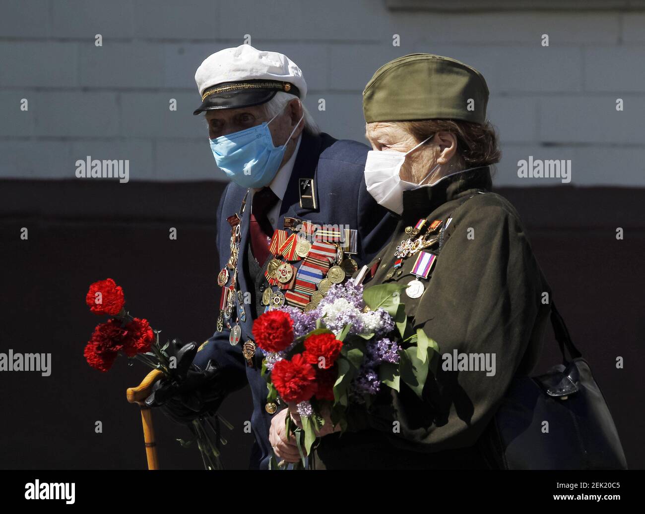 Veterans carry flowers while wearing face masks as a precaution during ...