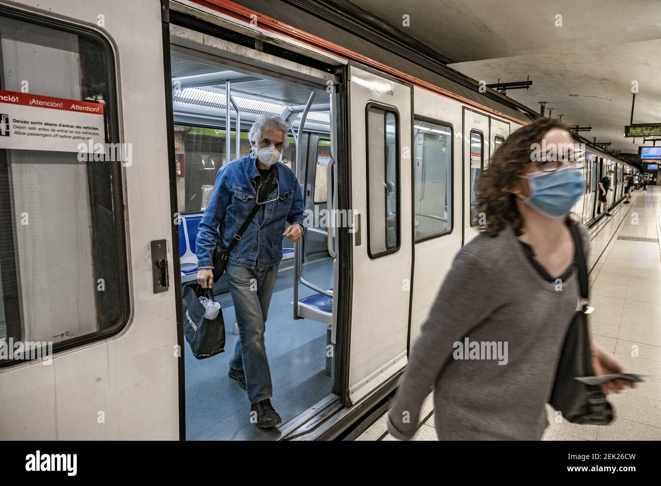 Passengers get out of the train while wearing face masks as a ...