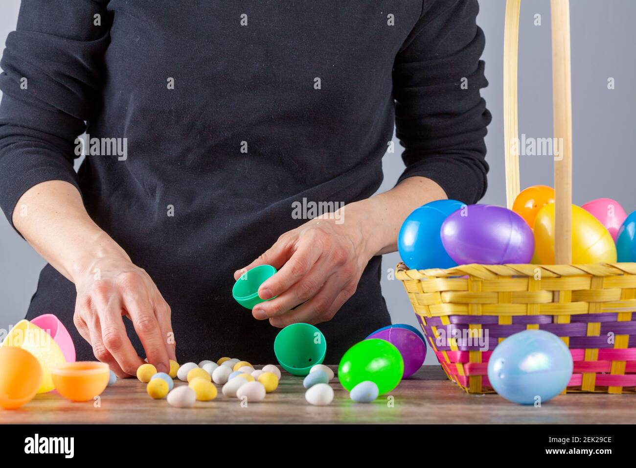 A caucasian woman is filling plastic easter egg shells with crisp sugar ...