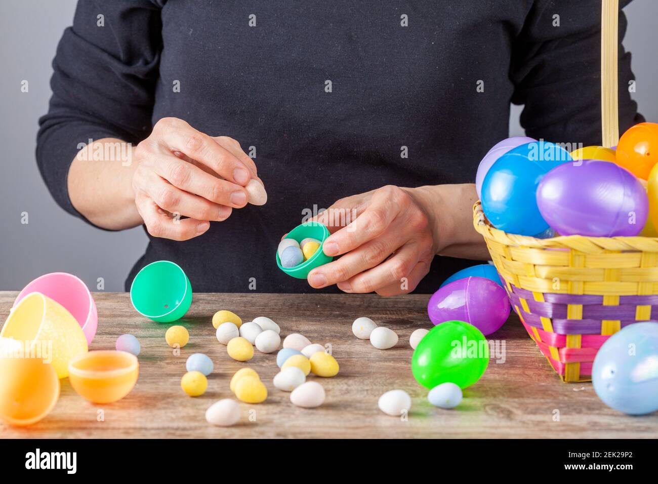 A caucasian woman is filling plastic easter egg shells with crisp sugar ...