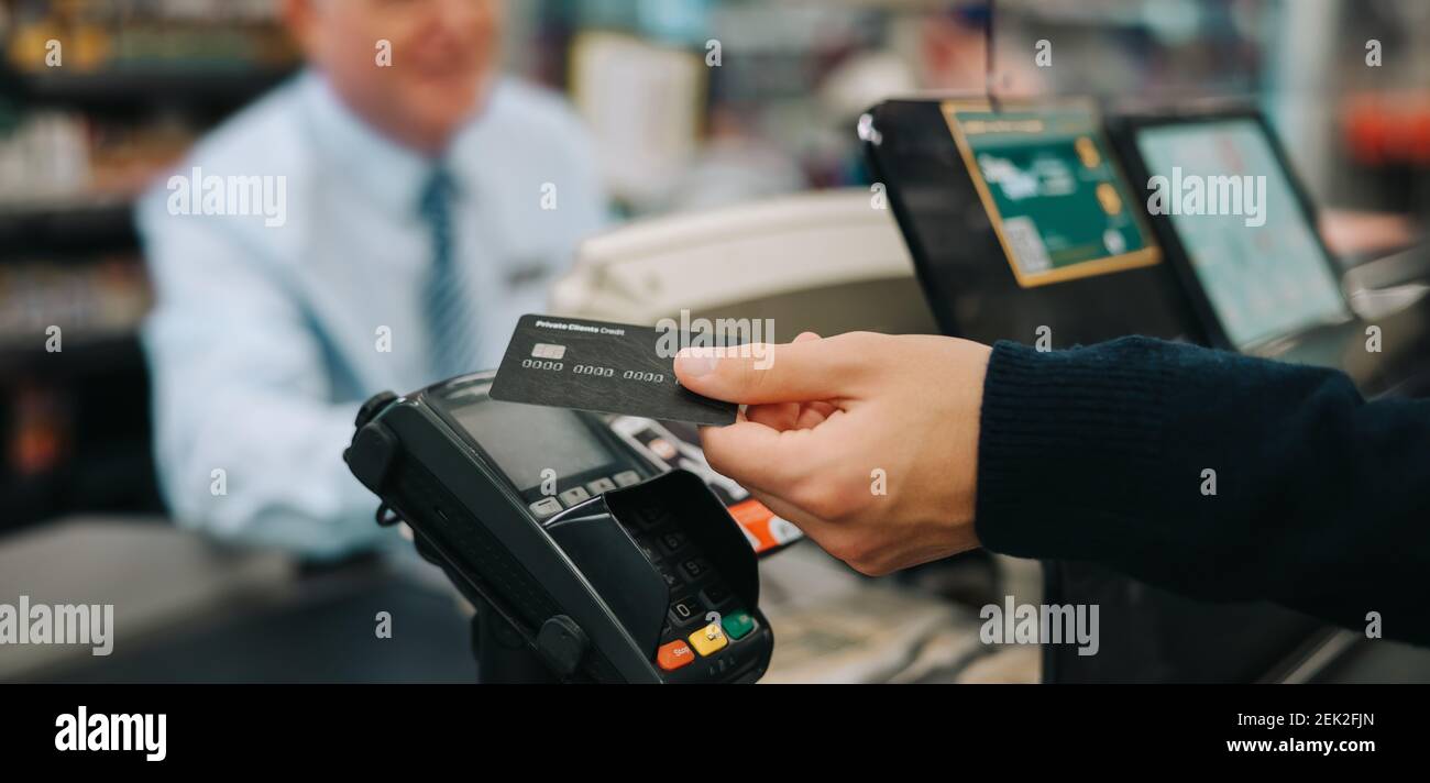 Close-up of a unrecognisable person using credit card to pay at grocery ...