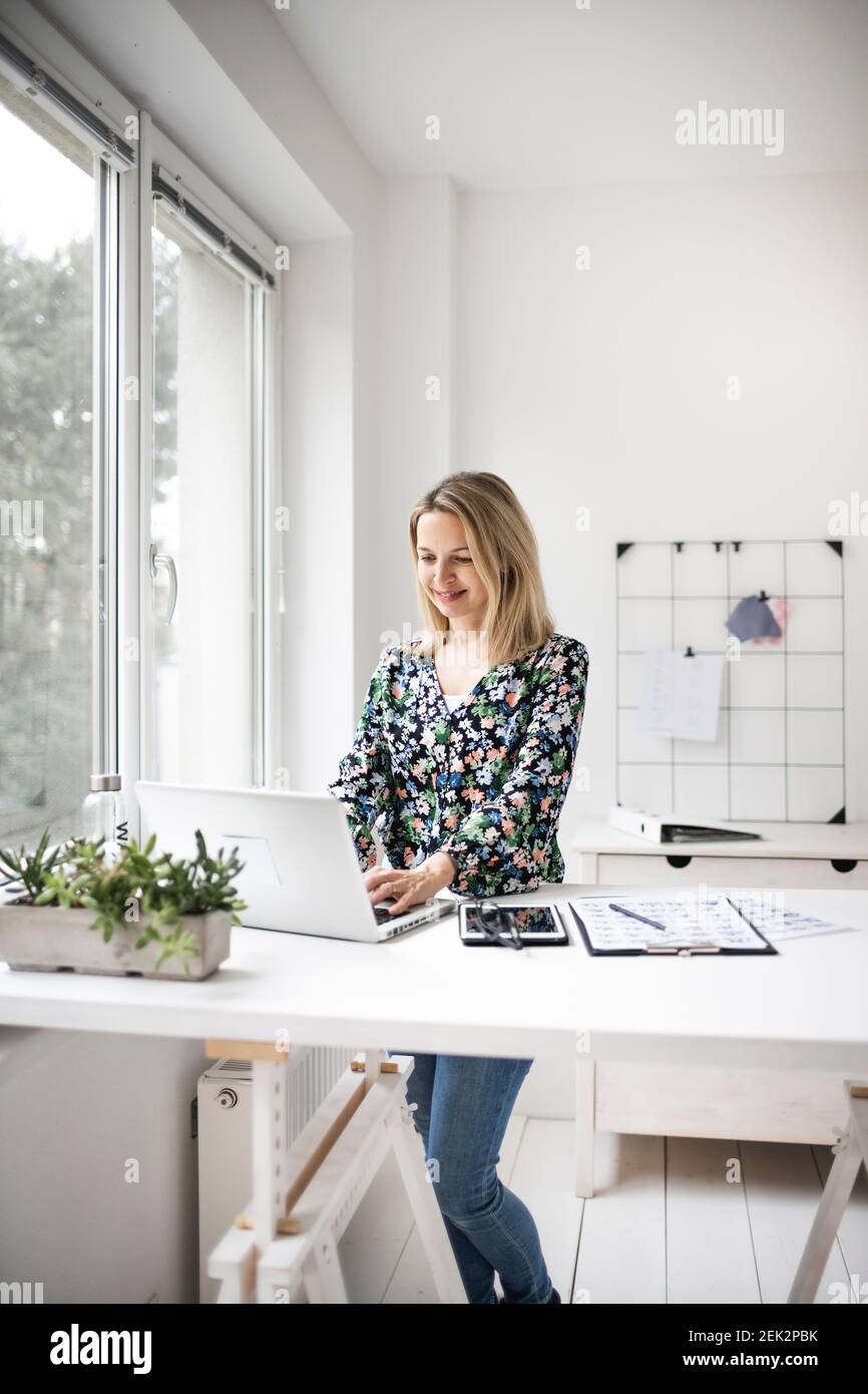 Businesswoman working at ergonomic standing workstation Stock Photo - Alamy