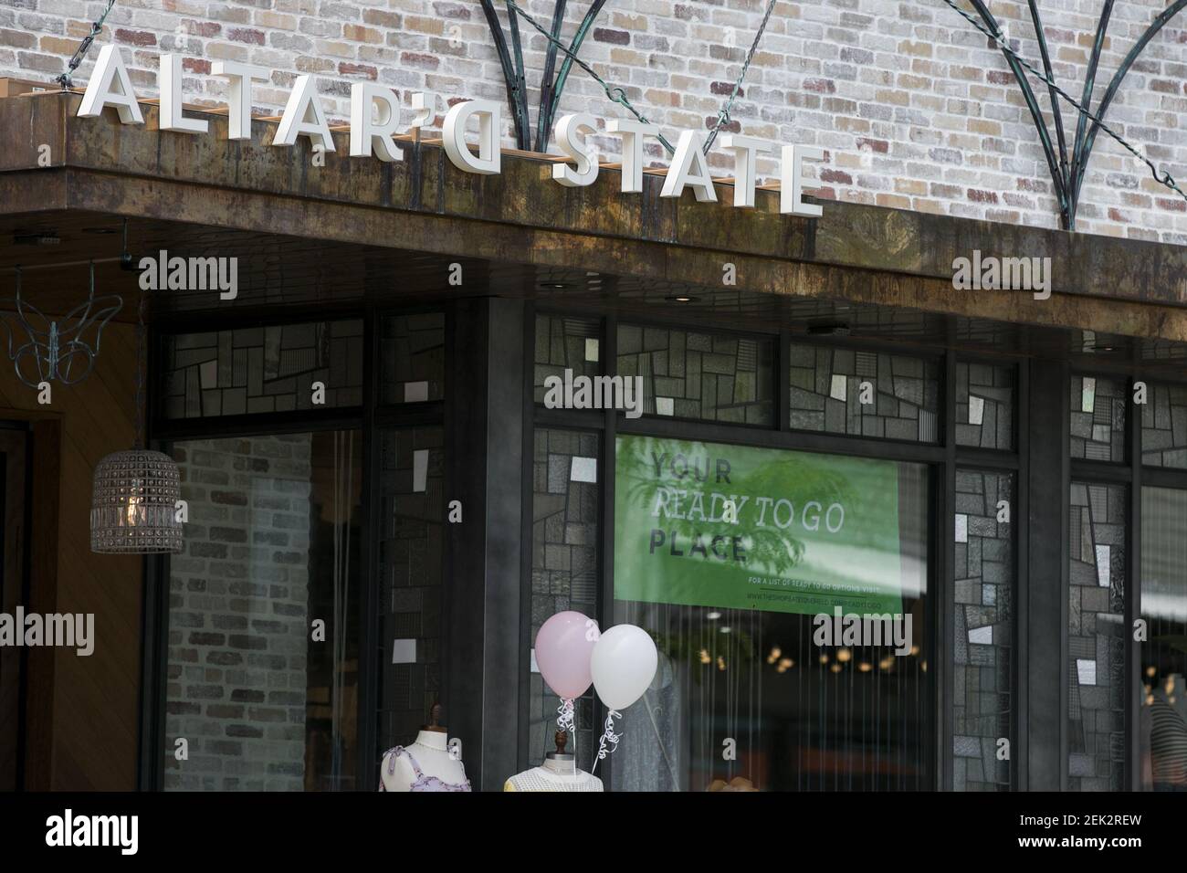 A logo sign outside of a Altar'd State retail store location in ...