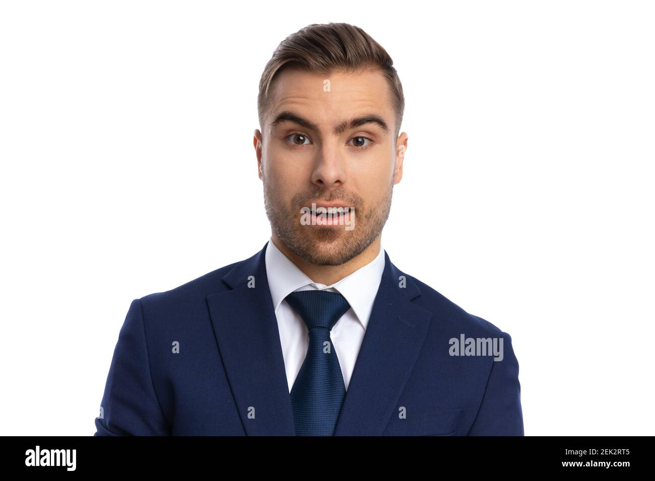 portrait of amazed guy in navy blue suit on white background opening ...