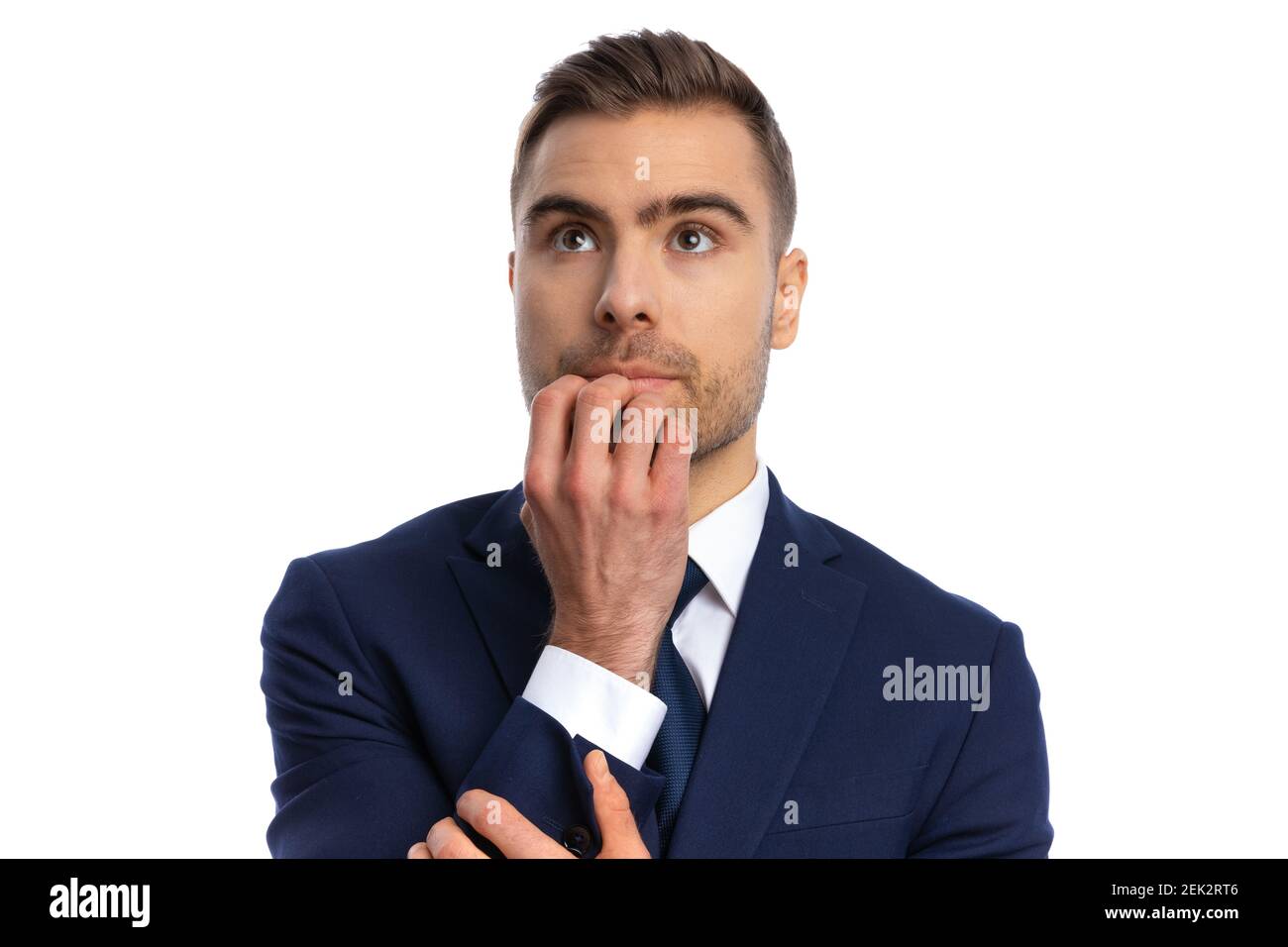 portrait of timid young man looking up, holding hand to chin and ...
