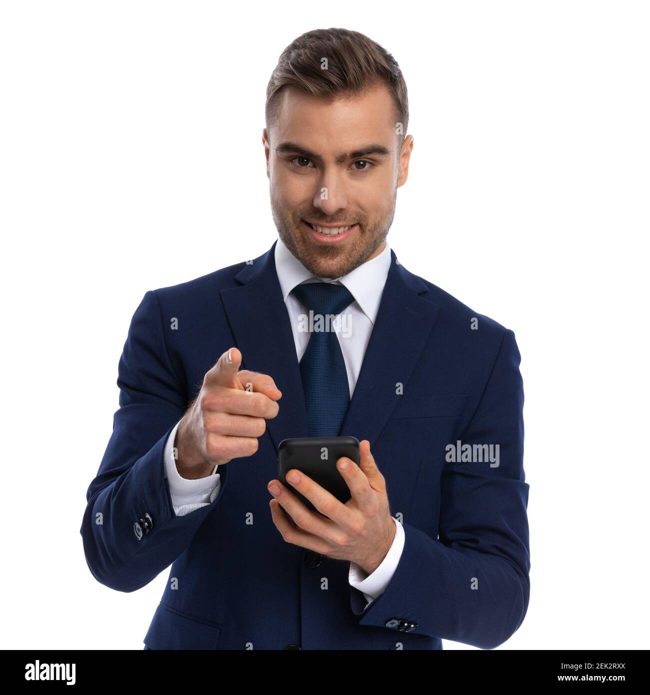 happy unshaved man in navy blue suit holding phone, pointing finger and ...
