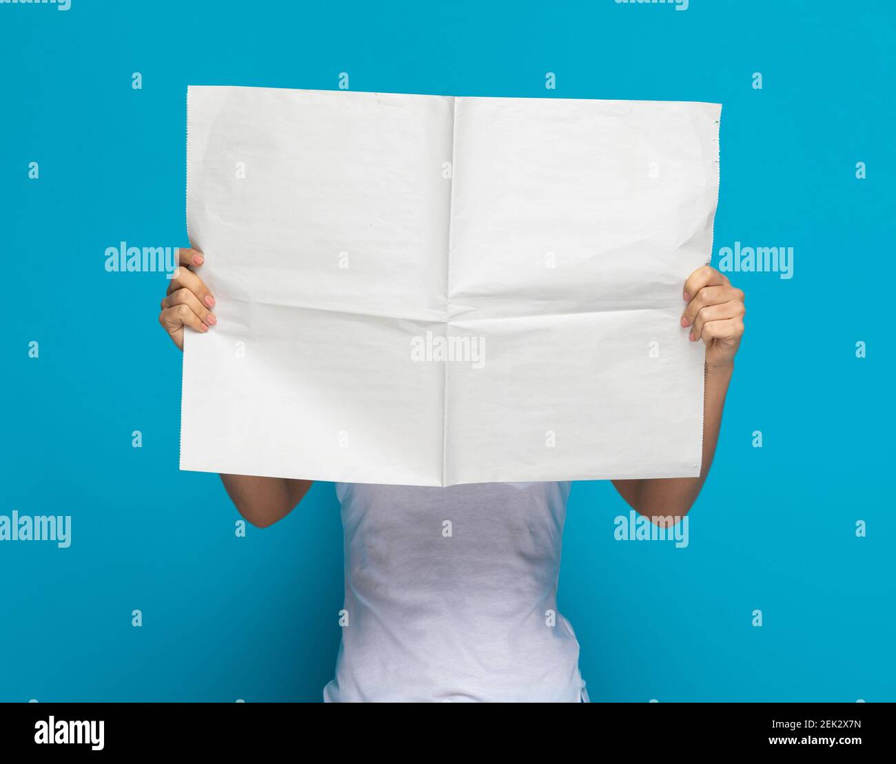casual woman reading her newspaper and hiding her face against blue ...