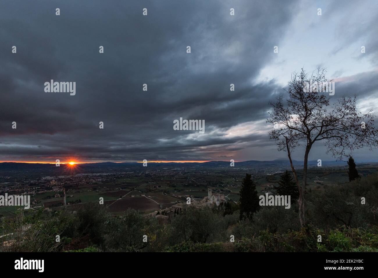 Distant sunset at Assisi town and St.Francis church with a moody sky ...