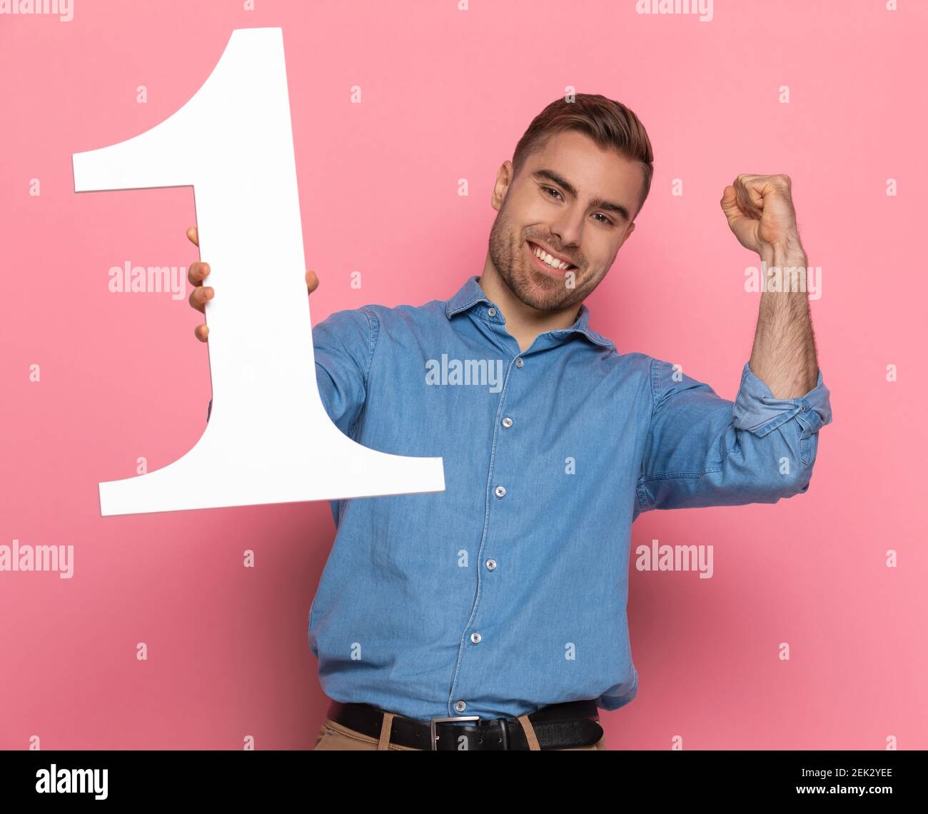 young casual guy in denim shirt holding number one, smiling and holding ...