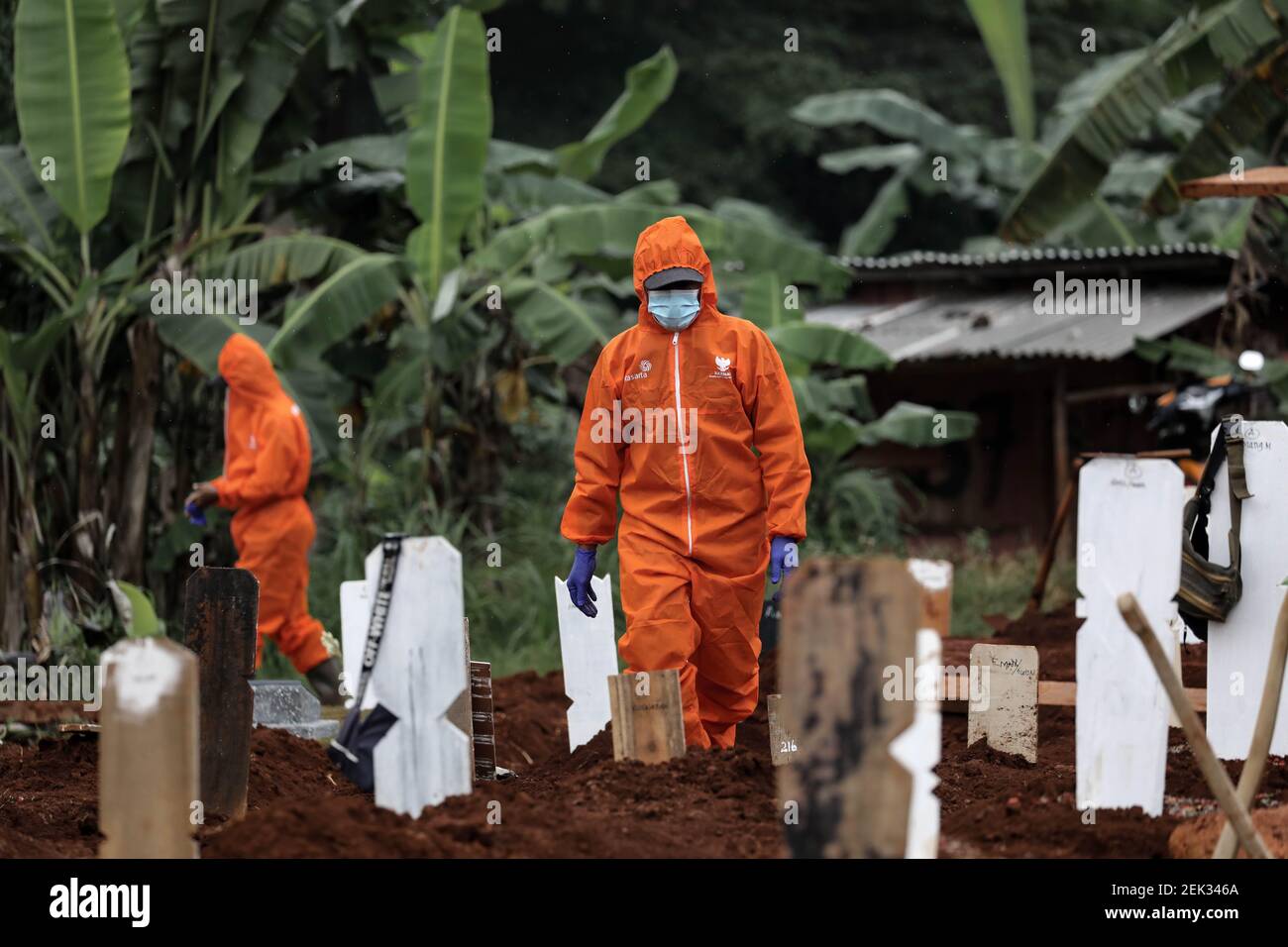 Cemetery workers wearing personal protective equipment (PPE) walking ...