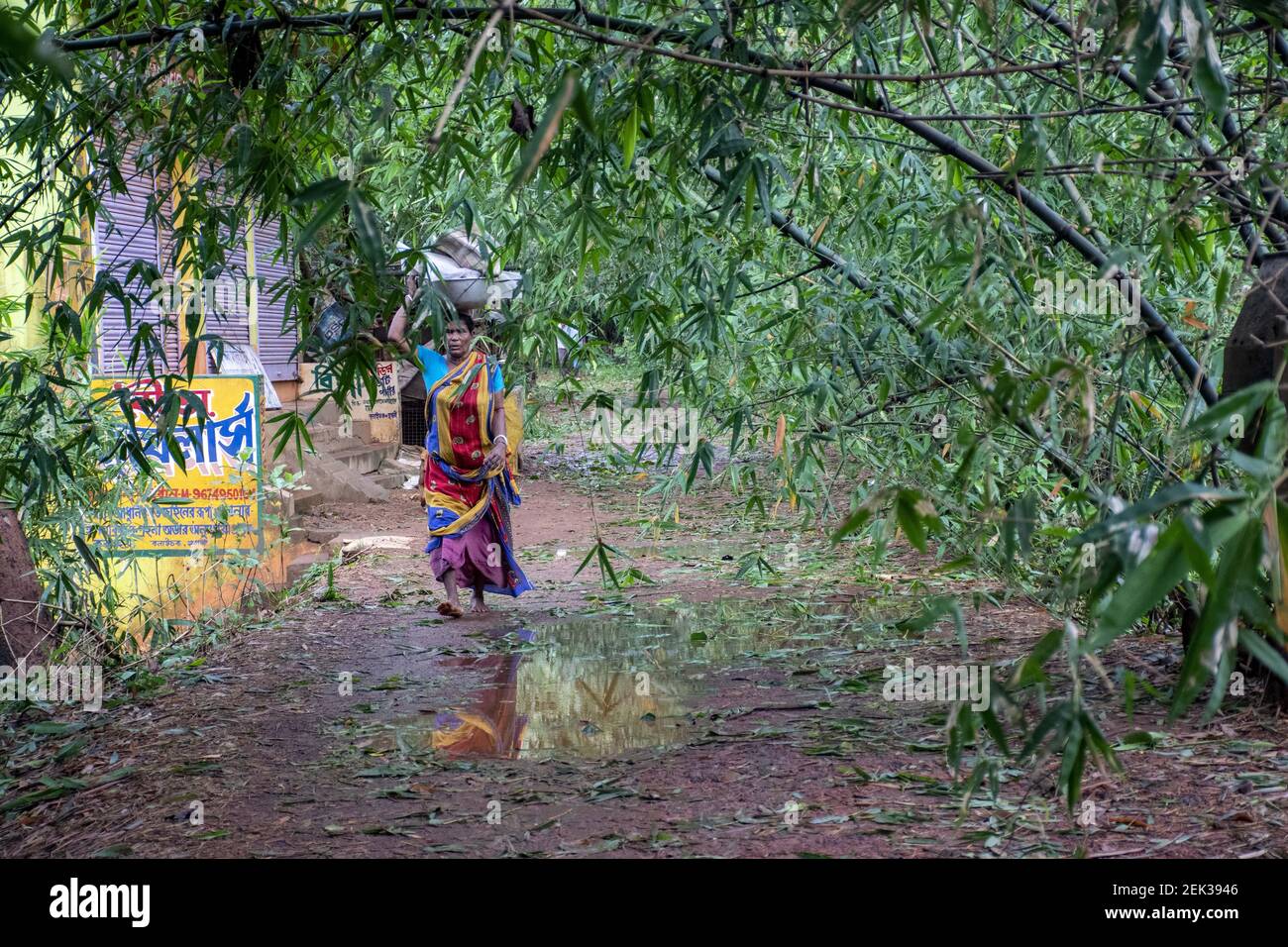 A woman walks while carrying a basket on her head after the Cyclone ...