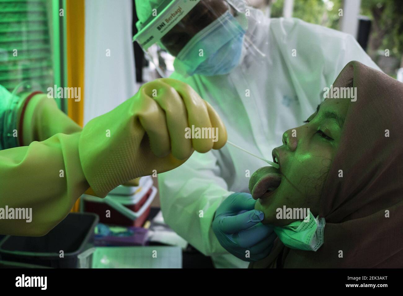 Medical workers wearing protective suits collect nasopharyngeal swab ...