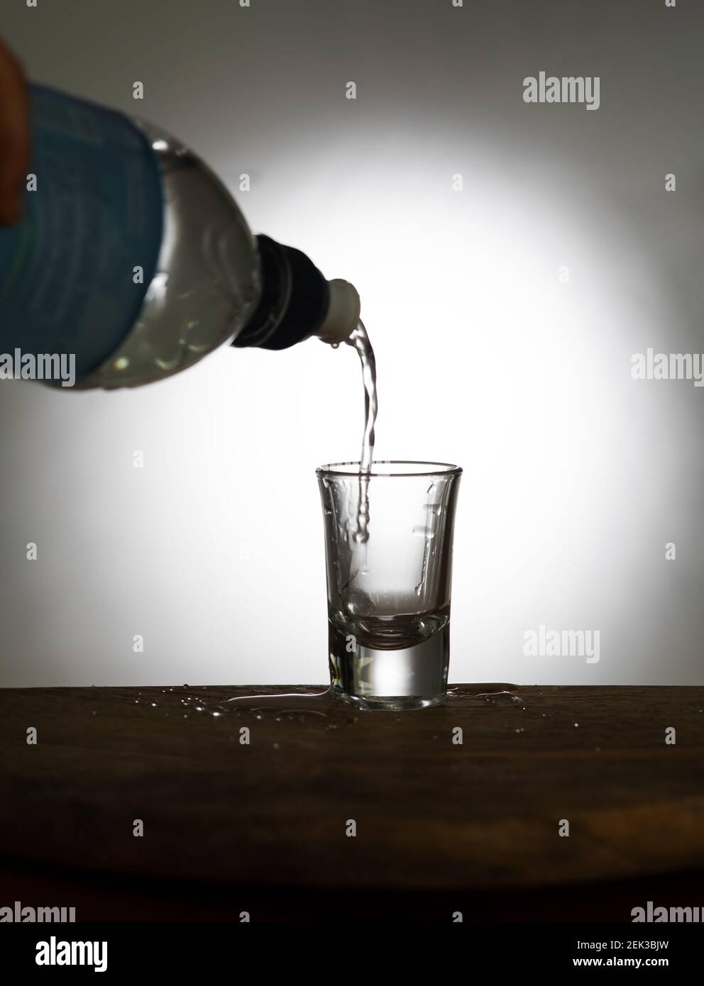 A stream of water flows into a glass from a bottle on an old wooden ...