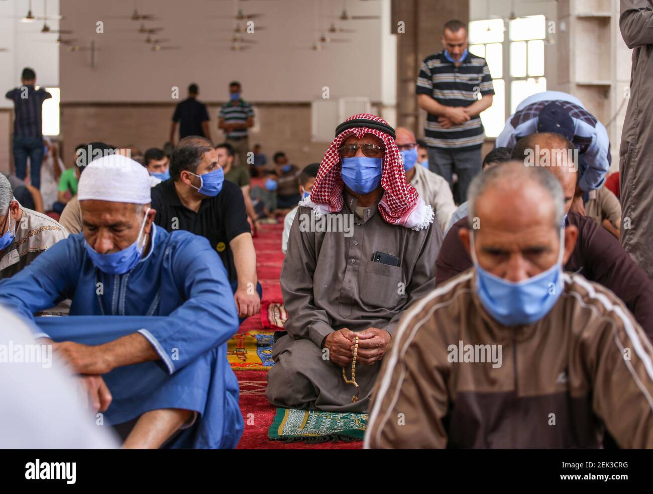 Muslim devotees sit at a social distance from each other as a ...