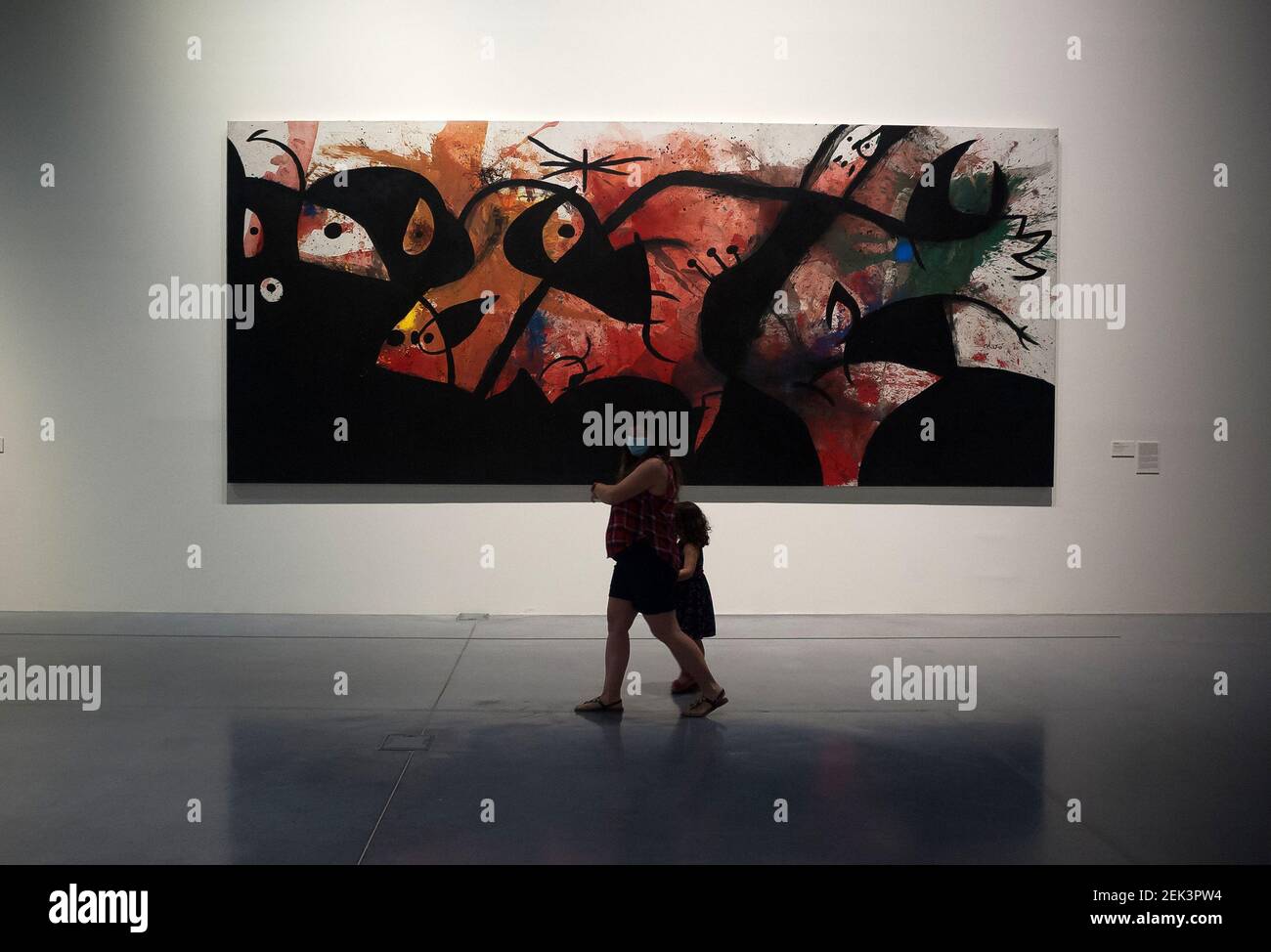 A woman wearing a face mask as a precaution, walking past a painting ...