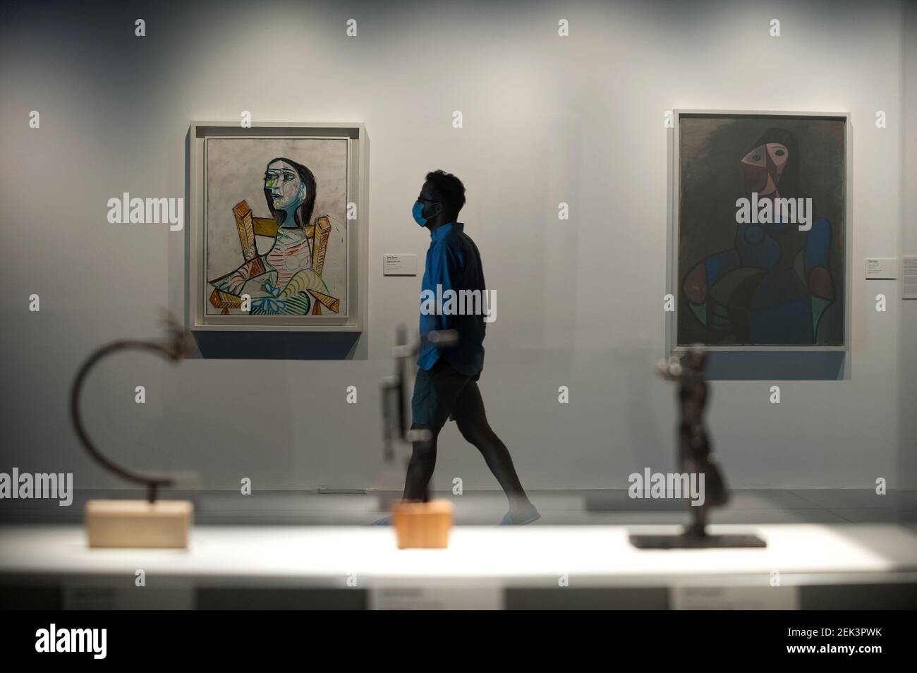 A visitor wearing a face mask as a precaution walks past a painting ...