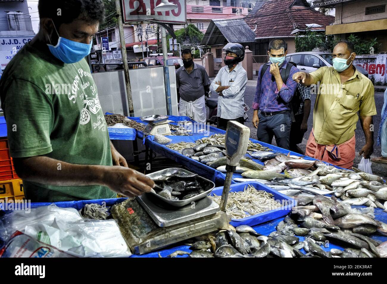 Men wearing face masks as a preventive measure while buying fish during ...