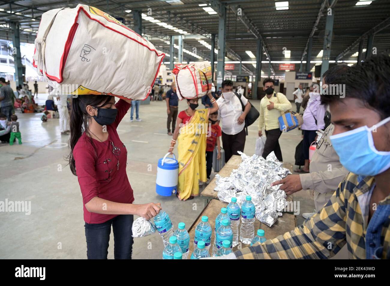 Migrants from Surat arrived by a special train collect food packets at ...