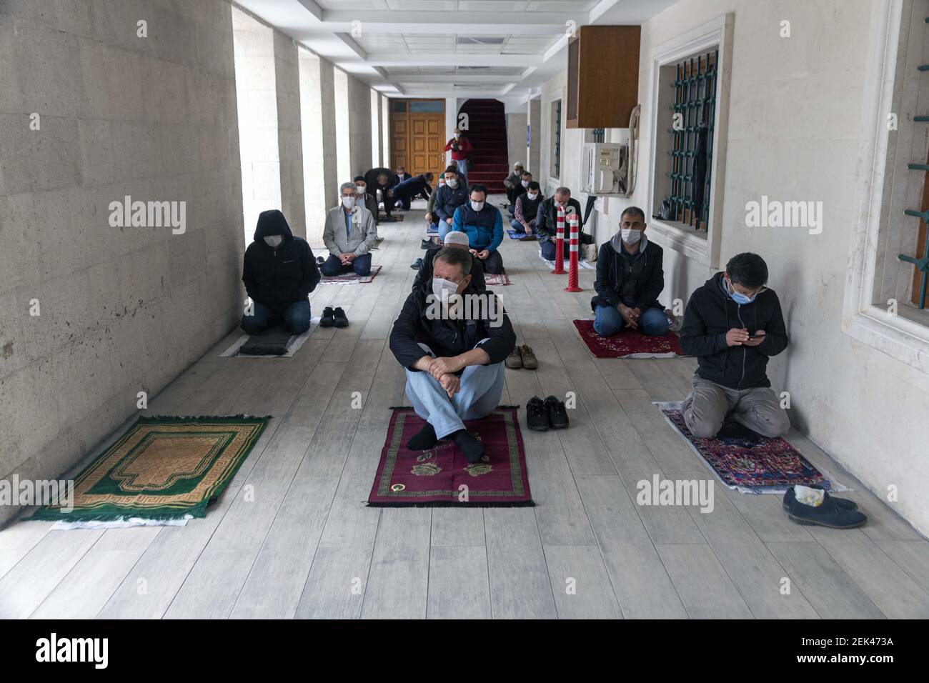 People wearing face masks perform Friday prayer, following the social ...