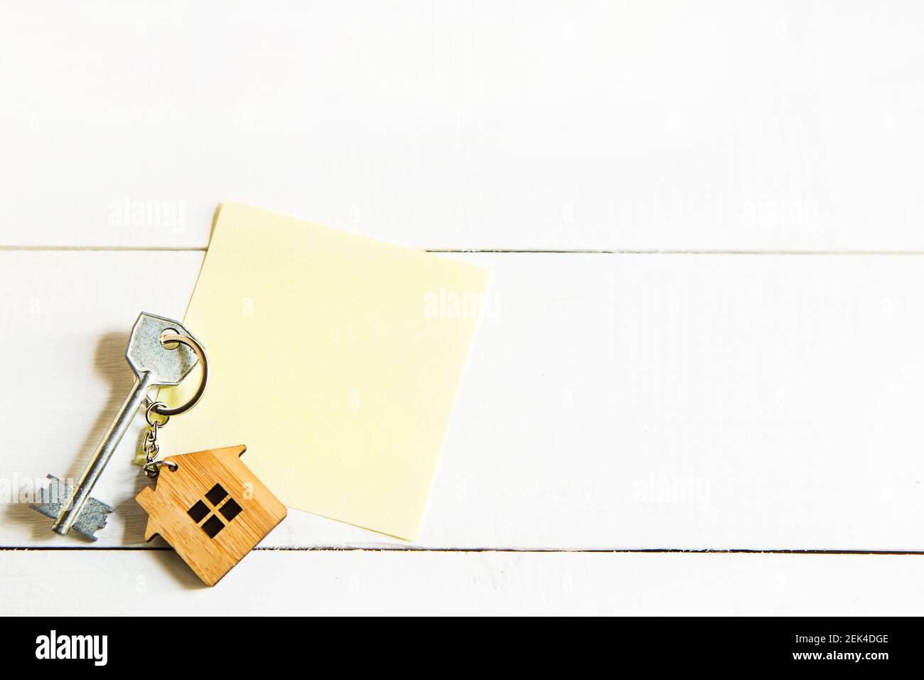 Keychain in the shape of wooden house with key on a white background ...