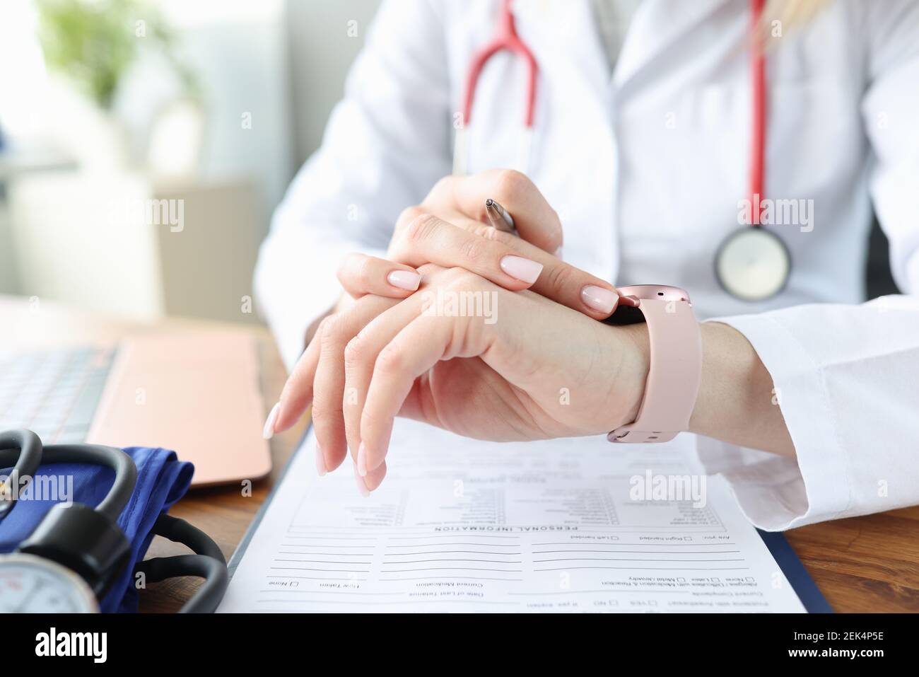 Doctor looks at clock at work table in medical office Stock Photo - Alamy