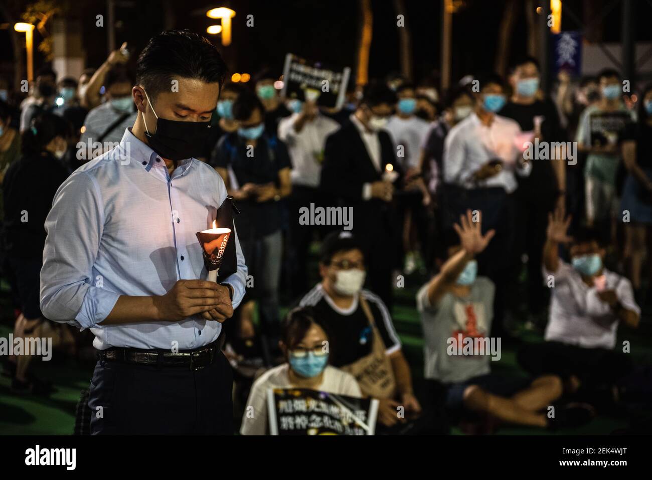A man bows his head while holding a candle during the anniversary rally ...