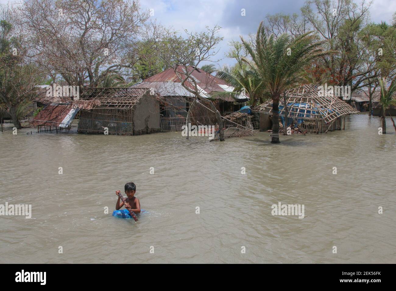 A boy riding a homemade plastic raft at his flooded house on the ...