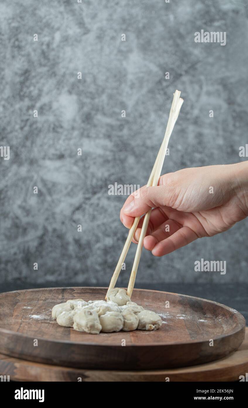 Hand holding a chopstick with a dumpling Stock Photo - Alamy