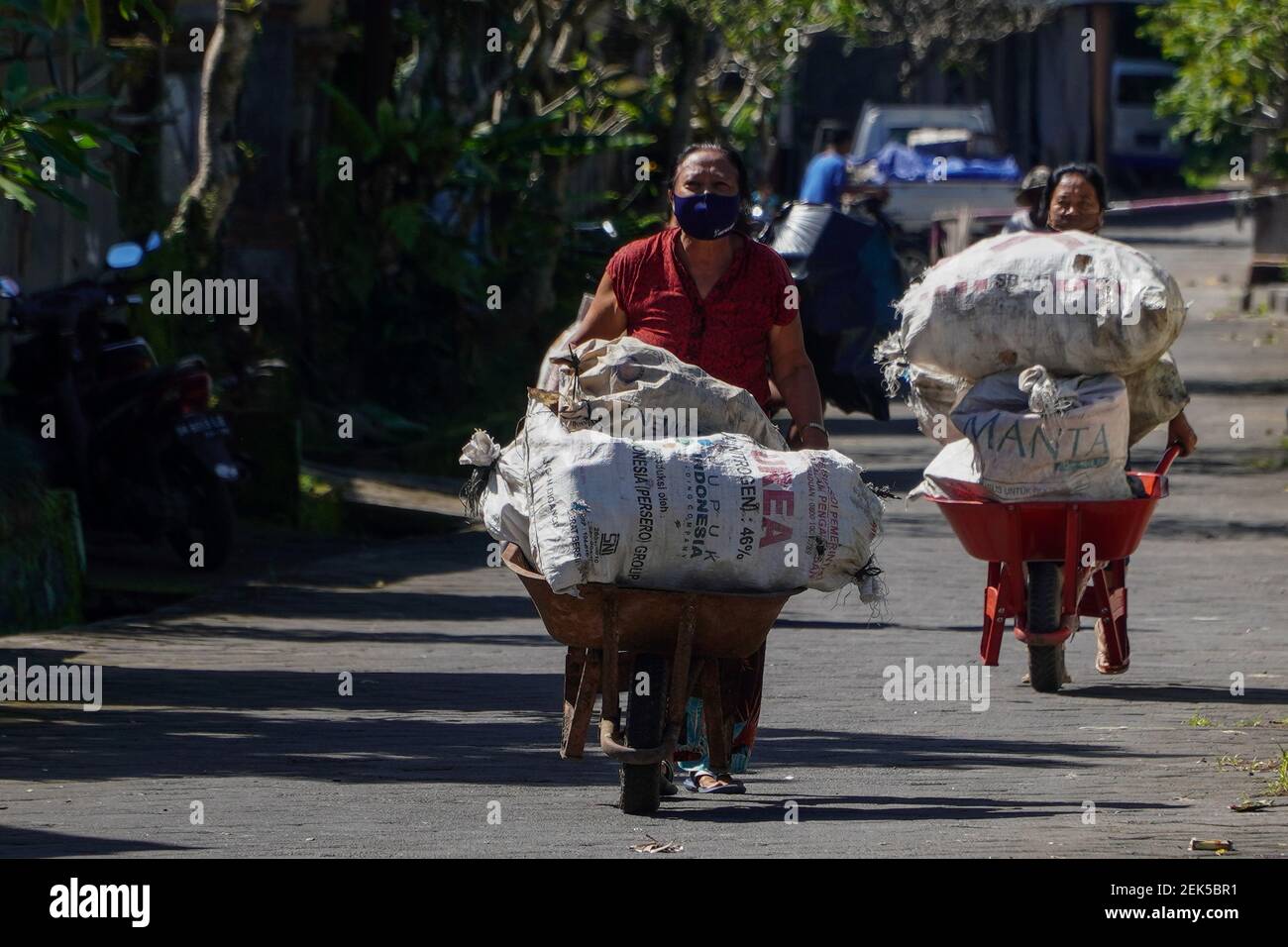 Woman pushing plastic waste on wheel barrows during the covid 19 crisis ...