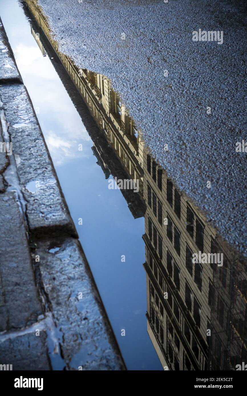 Chelsea building in New York reflected in a puddle in New York on ...