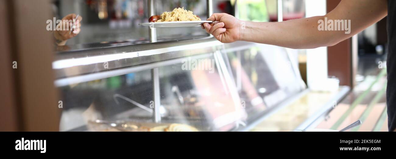 Man stand behind counter of ready-made food in dining room and hold ...