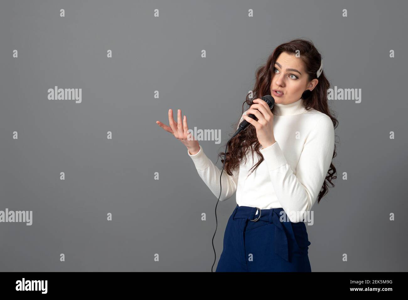 attractive female conference speaker during presentation, holds ...