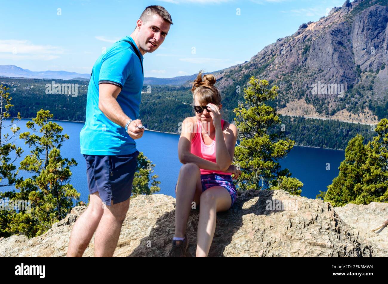 Cute young couple sitting on top of a cliff and taking a photo with a ...