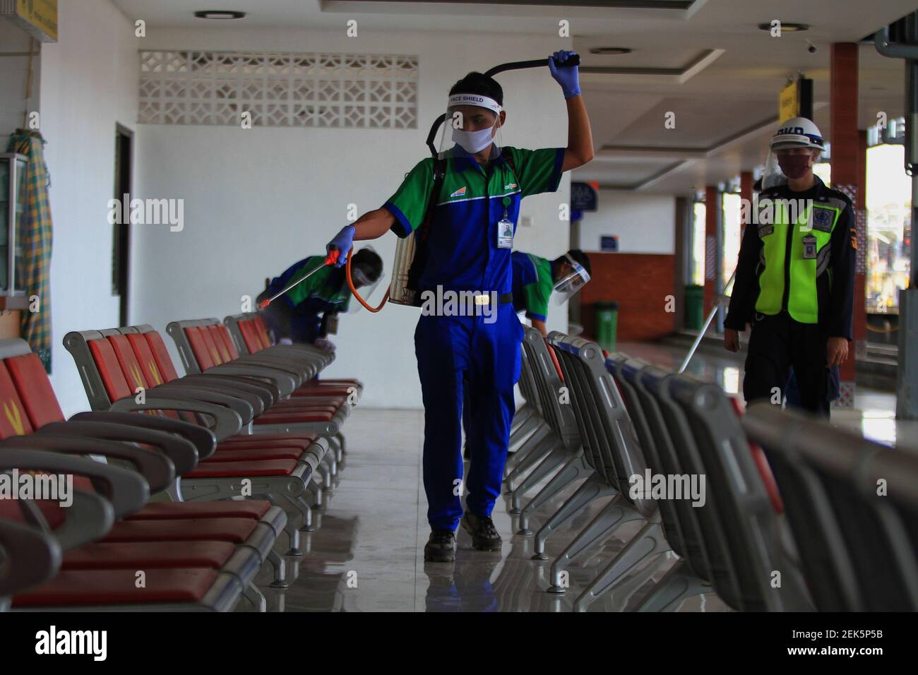 Workers wear a face shield and gloves sprays disinfectants as a ...