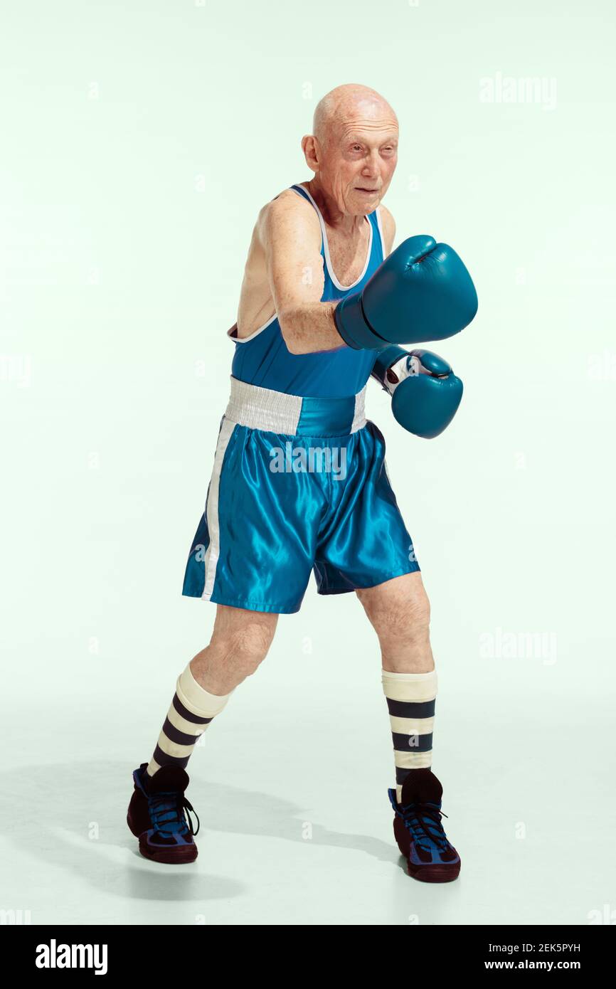 Punch. Senior man wearing sportwear boxing on studio background ...