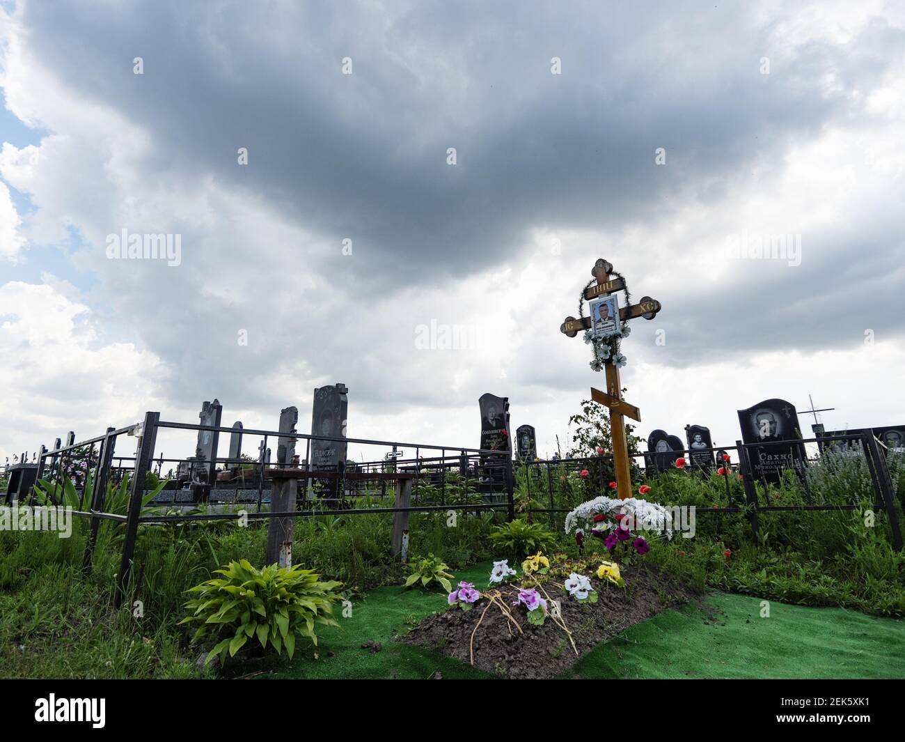A grave having a symbolic cross and decorated with flowers in an ...