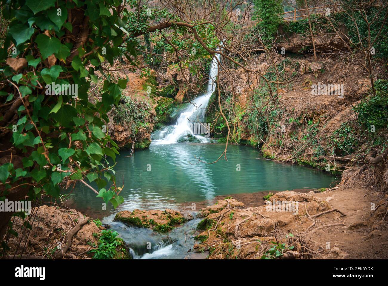 A large beautiful waterfall in a forest with blue water and trees Stock ...
