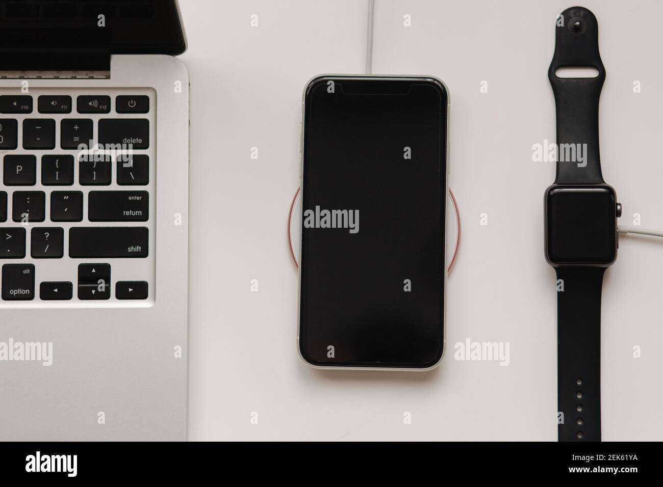 Laptop with smart watch and phone charging on wireless charger. Top ...