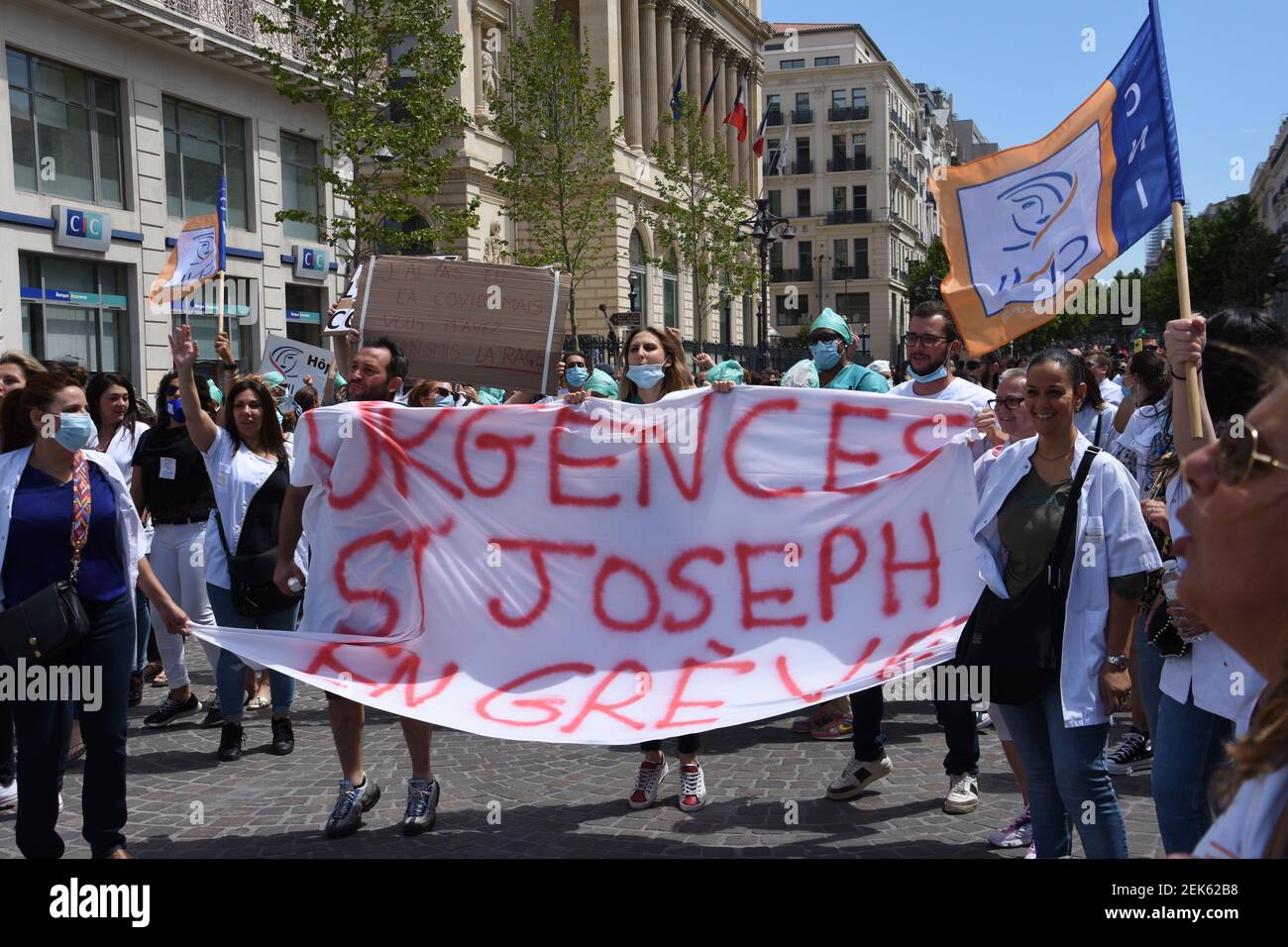 Healthcare workers wearing masks display a banner during the ...