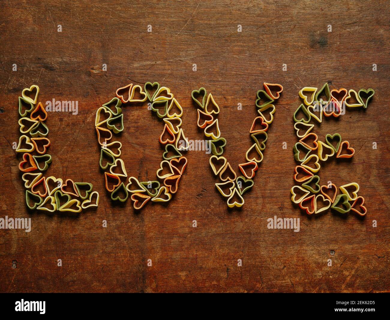Wood table with heart-shaped pasta making the word love Stock Photo - Alamy