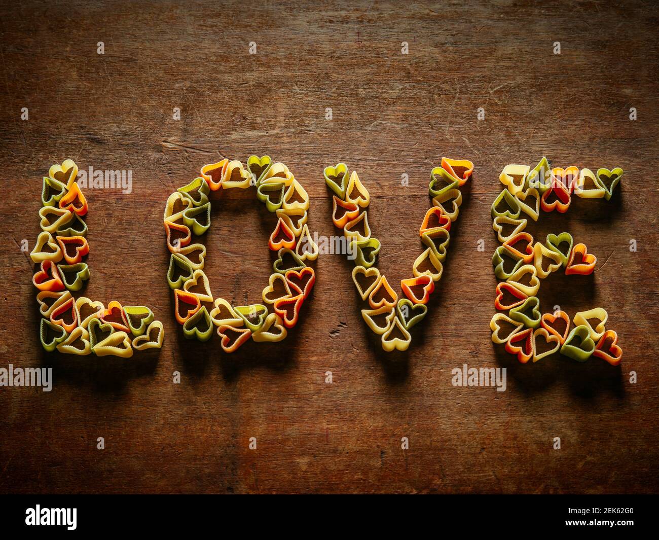 Wood table with heart-shaped pasta making the word love Stock Photo - Alamy