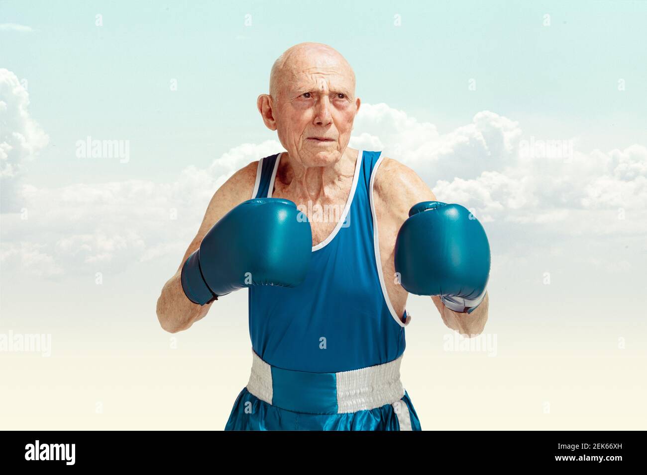Senior man wearing sportwear boxing isolated on sky background ...