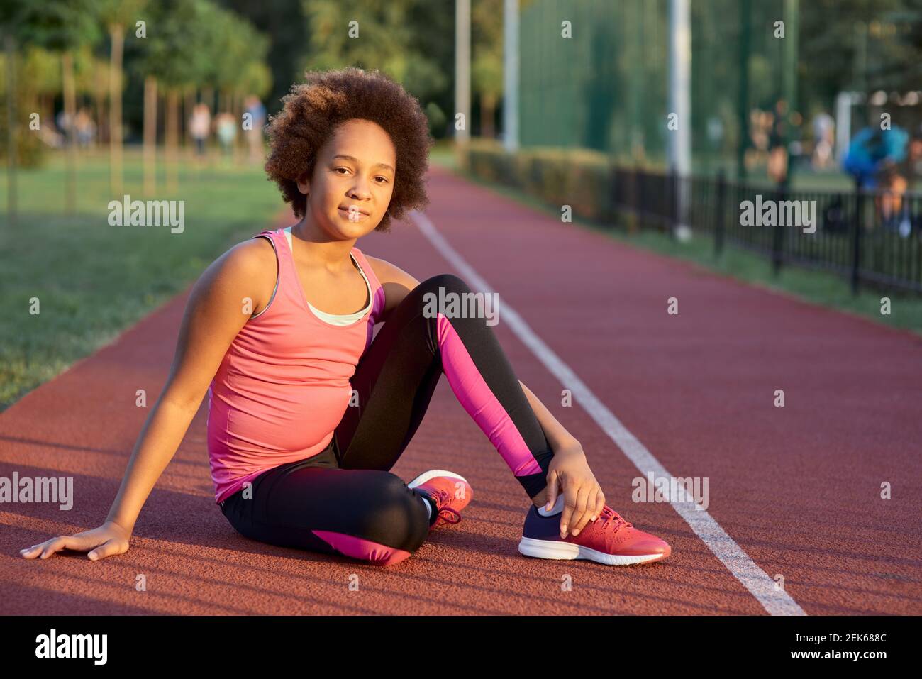 Adorable little girl sitting on running track at stadium Stock Photo ...