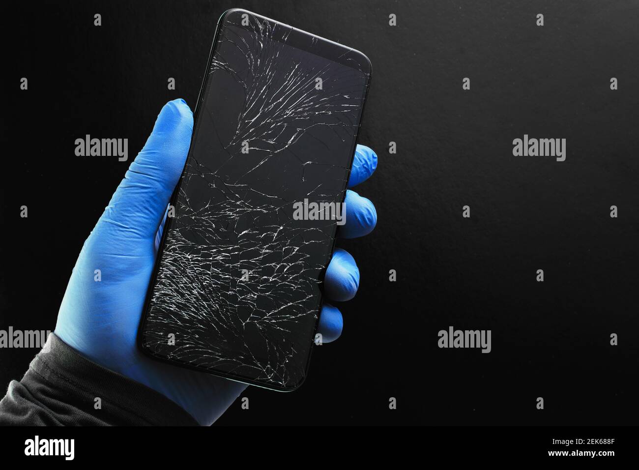 A broken touch phone with a cracked screen in your hand on a black ...